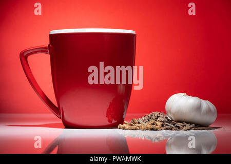 Red mug with small pile of garlic isolated on the red background Stock ...