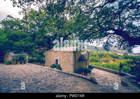 small church surrounded by high trees and colorful plants in autumn ...