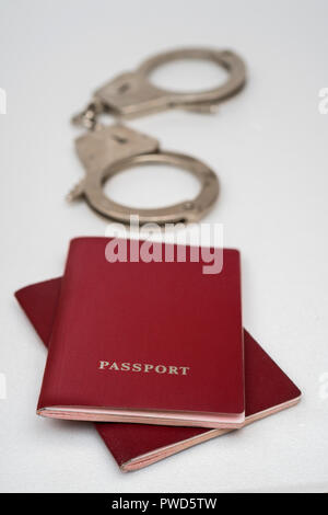 red passport on white background and handcuffs Stock Photo - Alamy