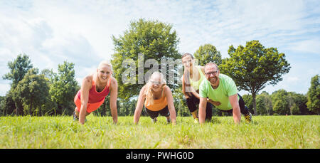Family doing push-ups in nature under guidance by a fitness coach Stock ...