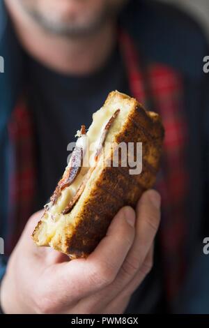 closeup of a man about to toast a ham and cheese sandwich on a sandwich ...
