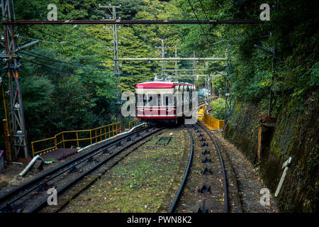 Modern red funicular is climbing a mountain slope, surrounded by ...
