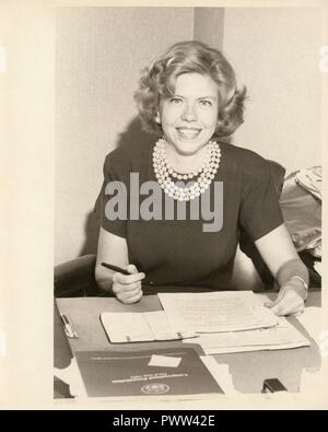 BARBARA UPTON IS SMILING SITTING AT HER DESK WITH SOME PAPER WORK IN ...