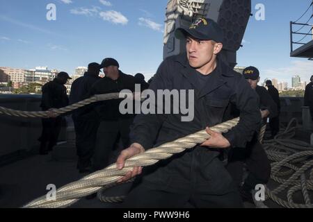 A U.S. Navy Seaman Apprentice heaves a line from guided-missile frigate ...