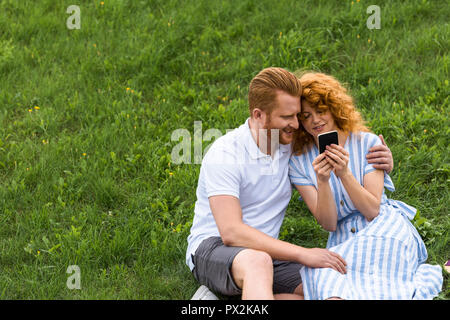 Handsome man showing red haired woman colleague funny photos on phone ...