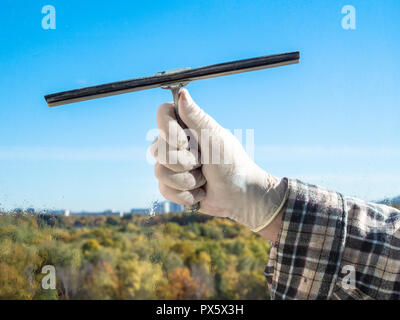 male hand wipes a home window glass in city in sunny autumn day Stock ...