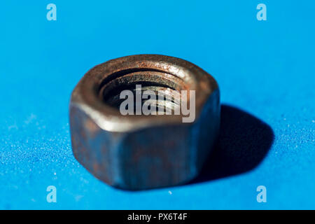 old rusty nut isolated on light blue background Stock Photo - Alamy