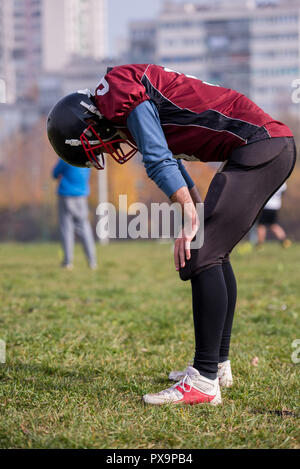 A tired american football player resting after hard training at field ...