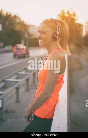 A beautiful blonde woman enjoys music while showcasing her trendy denim ...