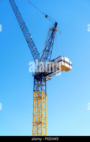 A very tall crane against a clear blue sky with clouds and the gable ...