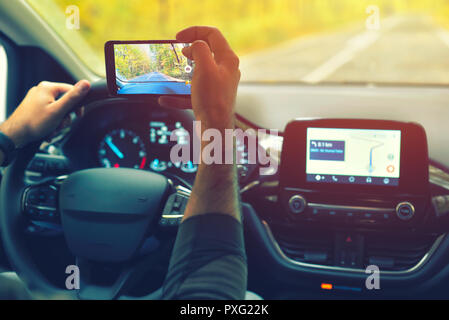 Male driver using smartphone to capture pictures of road, while driving ...