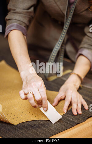 Professional adult female tailor marking cloth pattern with chalk at ...