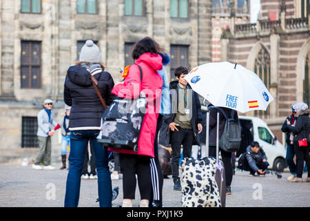 AMSTERDAM, NETHERLANDS- MARCH, 2018: Tourists at Dam Square on a cold ...