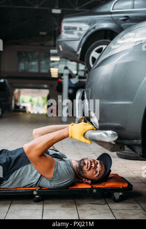 Workman mechanic working under car in auto repair shop Stock Photo - Alamy