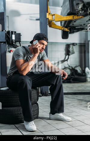 mechanic talking on smartphone and holding wrench in auto repair shop ...