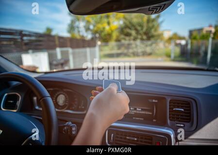 Person opening automatic property gate with remote control from car ...