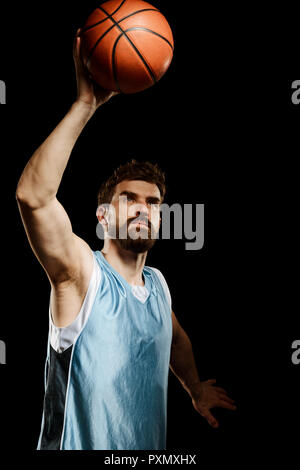 Muscular basketball player passing the ball over grey background Stock ...