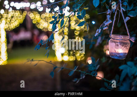 Hanging glasses with candles at night wedding party on garden ...