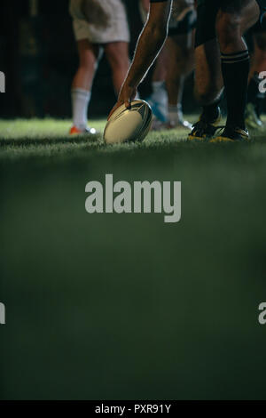 Rugby player picking up ball Stock Photo - Alamy