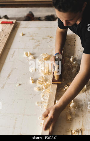 Carpenter using plane on piece of wood in workshop Stock Photo - Alamy