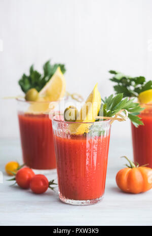Glasses of bloody mary cocktail garnished with bacon and lime on dark ...