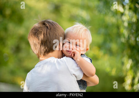 Little boy carrying crying brother on his back, Alabama Stock Photo - Alamy