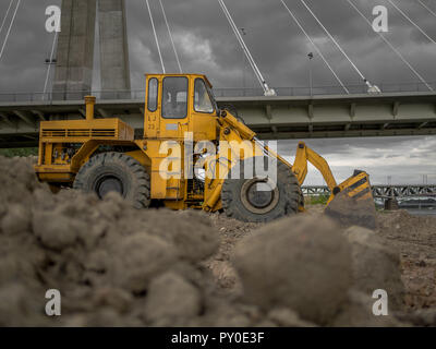 A yellow bulldozer next to a bridge Stock Photo - Alamy