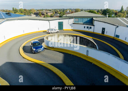 Spiral ramp of multistorey car park lit up at night with a large arrow ...