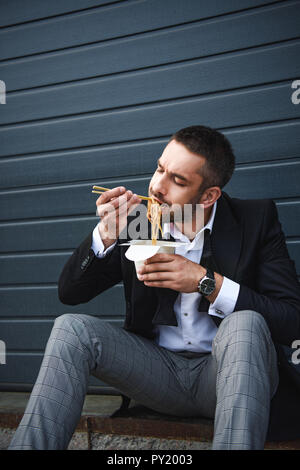 Hungry man in suit eating his sandwich in hurry during short break ...