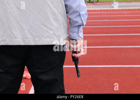 Race official holding a starting gun at the beginning of a track event ...