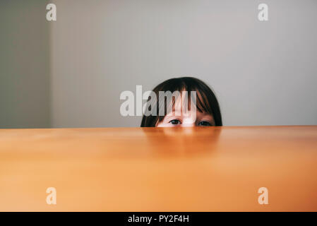 Girl hiding behind a table Stock Photo - Alamy