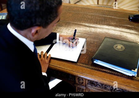 President Barack Obama writes at his desk in the Oval Office 3/3/09 ...