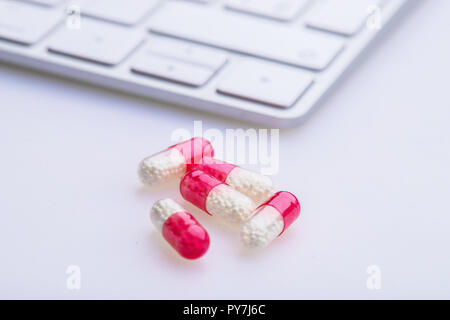 A bunch of pills next to the computer keyboard Stock Photo - Alamy