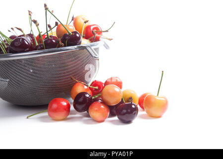 Steel colander with ripe berries of red sweet cherry and several ...