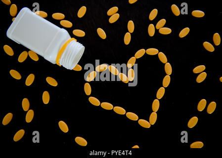 Yellow pills placed in a heart shape on the black table Stock Photo - Alamy