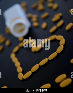 Yellow pills placed in a heart shape on the black table Stock Photo - Alamy