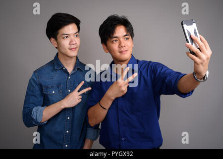 Stylish handsome asian guy taking picture on smartphone and smiling ...