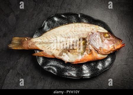 top view of fish skeleton bones and flavor peppers on slate background ...