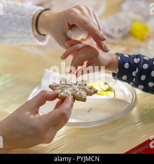 Mom helps her daughter decorate the cookies in the form of snowflake ...