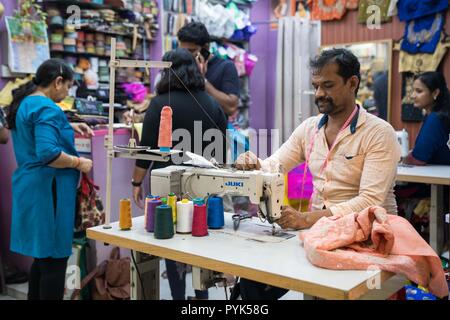 An Indian tailor seen working on Indian traditional clothings at his ...