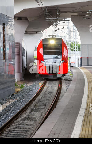 Modern red train approaching the train station Stock Photo - Alamy