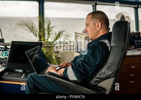 Marine navigational officer is using laptop or notebook at sea Stock ...