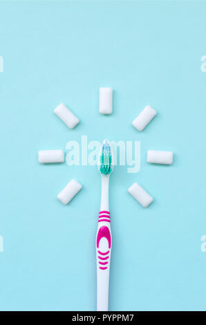 Toothbrush and chewing gums lie on a pastel pink background. Top view ...