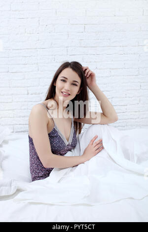 Beautiful woman waking up in her bed in the bedroom, she is stretching ...