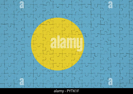 Palau flag is depicted on a puzzle, which the man's hand completes to ...