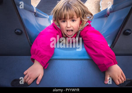Young child sliding backwards down a playground slide Stock Photo - Alamy