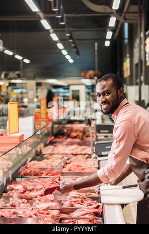 Young handsome butcher man holding meet steak standing over isolated ...
