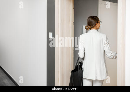 Young business woman entering the apartment returning from the work to ...
