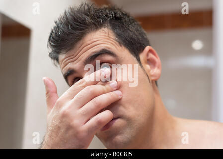 Handsome man inserting contact lens Stock Photo - Alamy