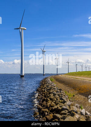 A long line of offshore wind turbines stretches across the clear ...